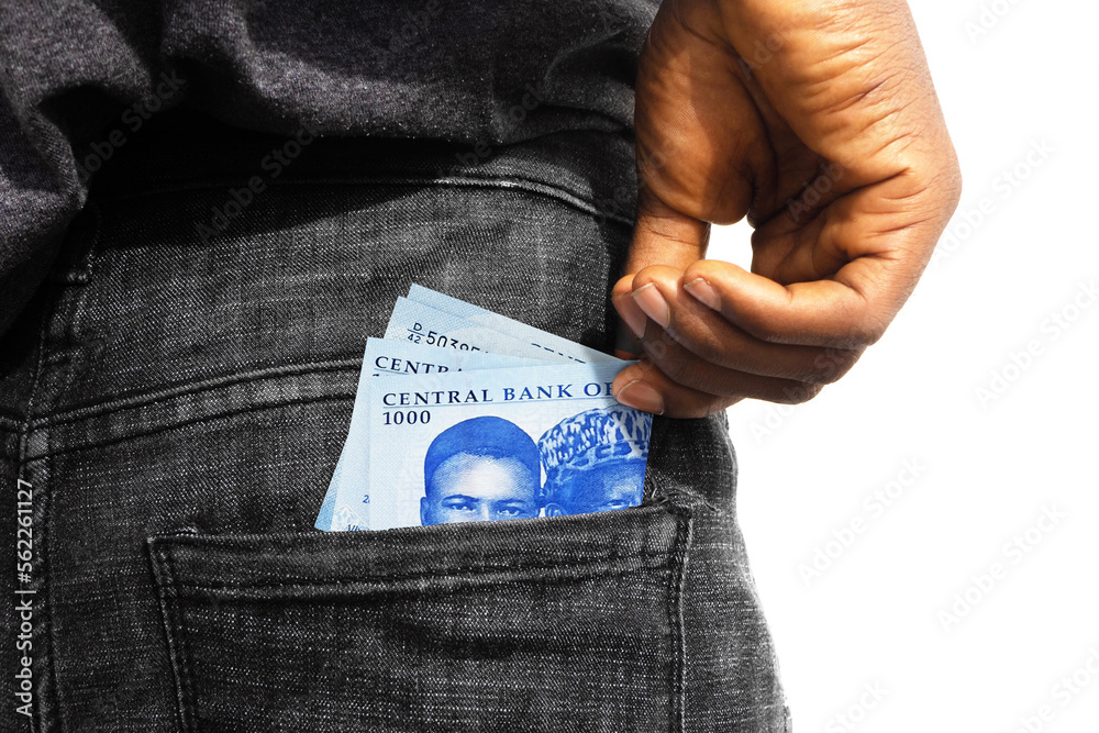 Black lady putting few Nigerian naira notes into her back pocket ...