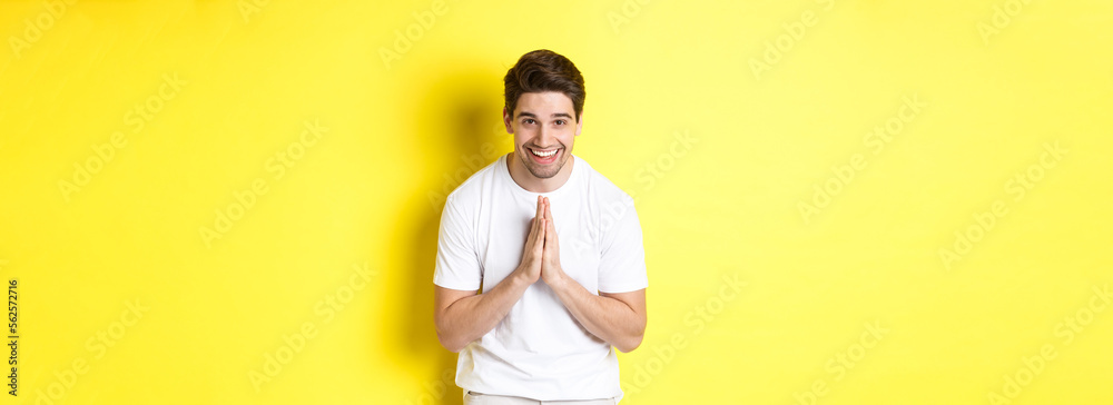 Handsome guy saying thank you, bowing and holding hands in namaste ...