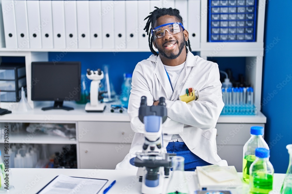 African man with dreadlocks working at scientist laboratory happy face smiling with crossed arms ...