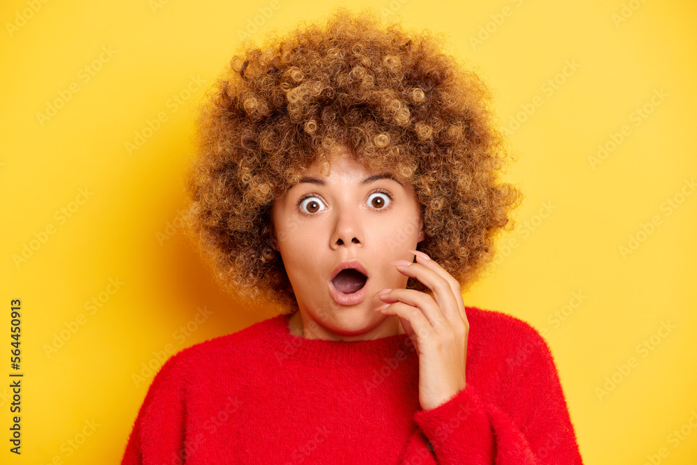 Worried woman looks nervously starring with scare look, has curly hair ...
