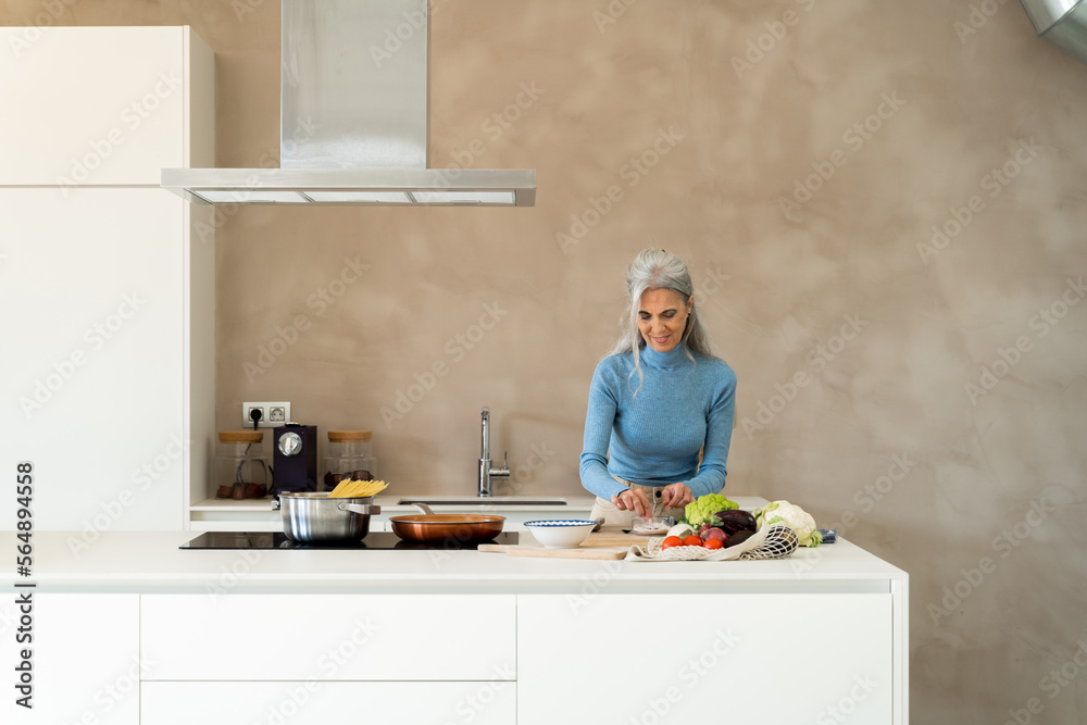 Foto de Stock Mature woman cooking in kitchen | Adobe Stock