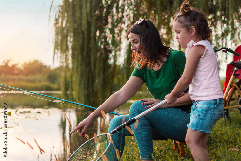 Fishing with mom. Mother and daughter fishing together on the river ...