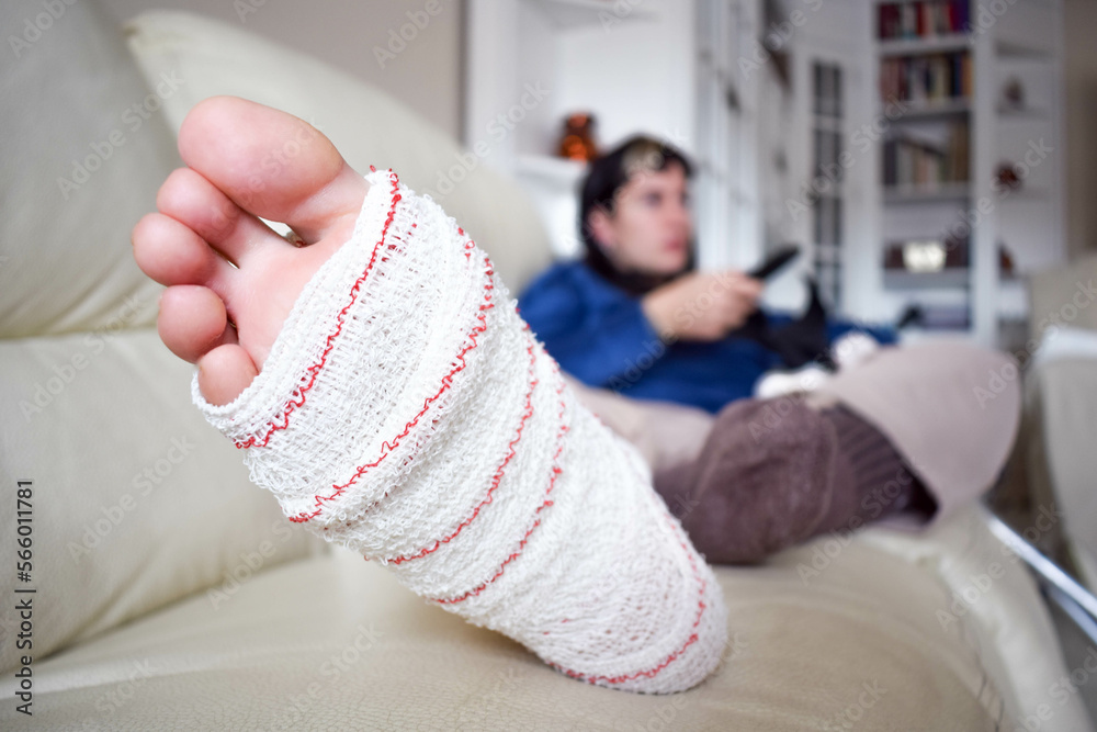 Young woman on couch at home with crutches and orthopedic plaster ...