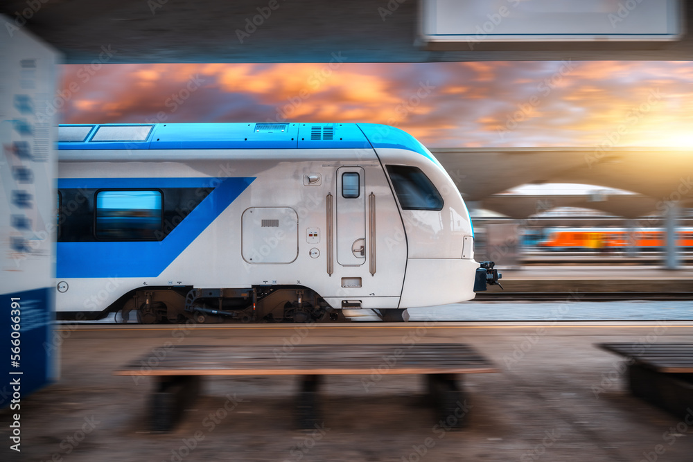 Blue high speed train in motion on the railway station at sunset. Fast ...