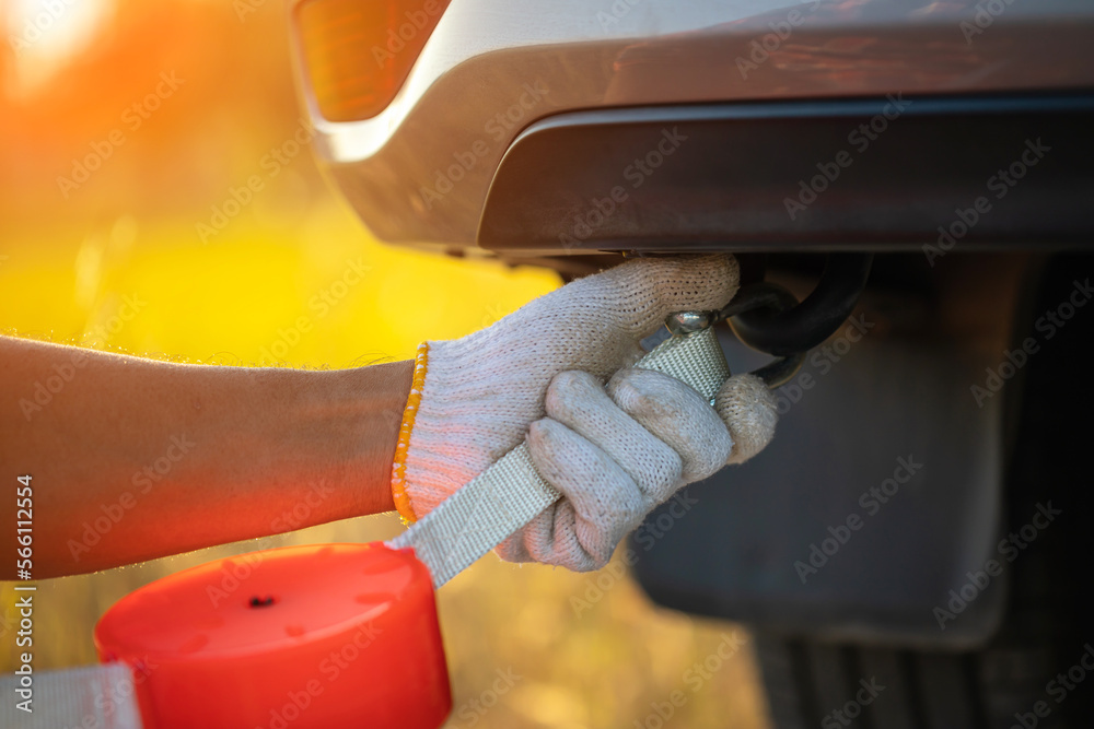 Man holding emergency car towing line and hook on backside of car on ...