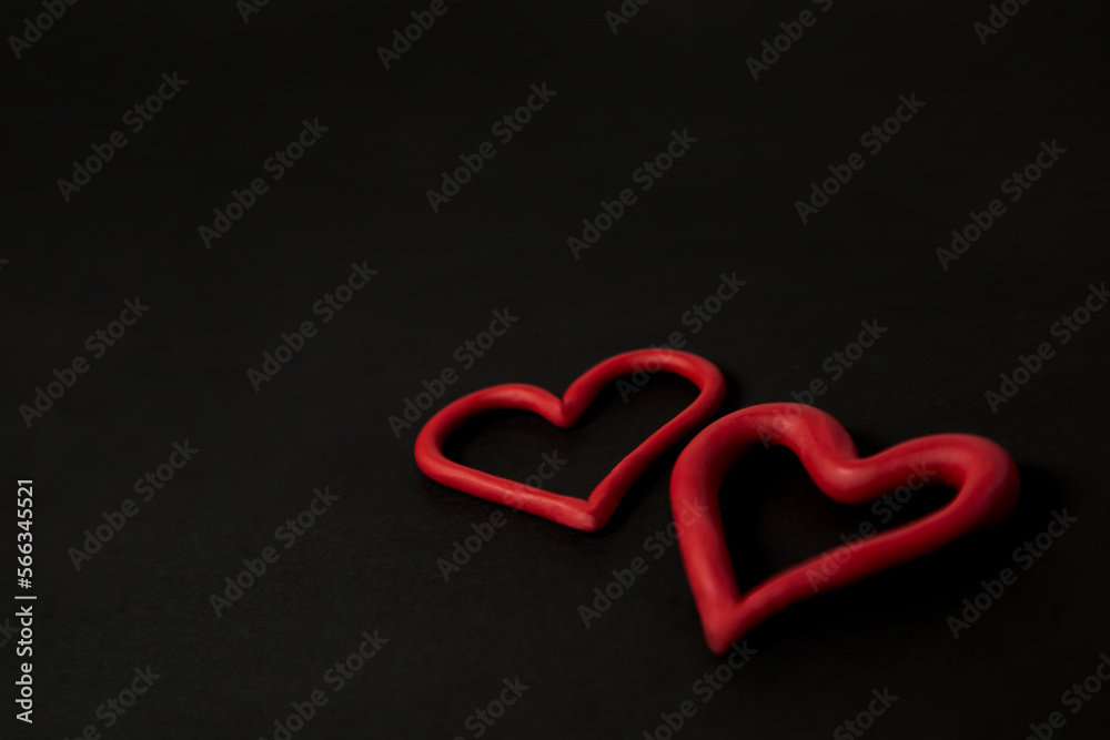 Manos formando corazón el fondo negro y corazones hechos en plastilina ...