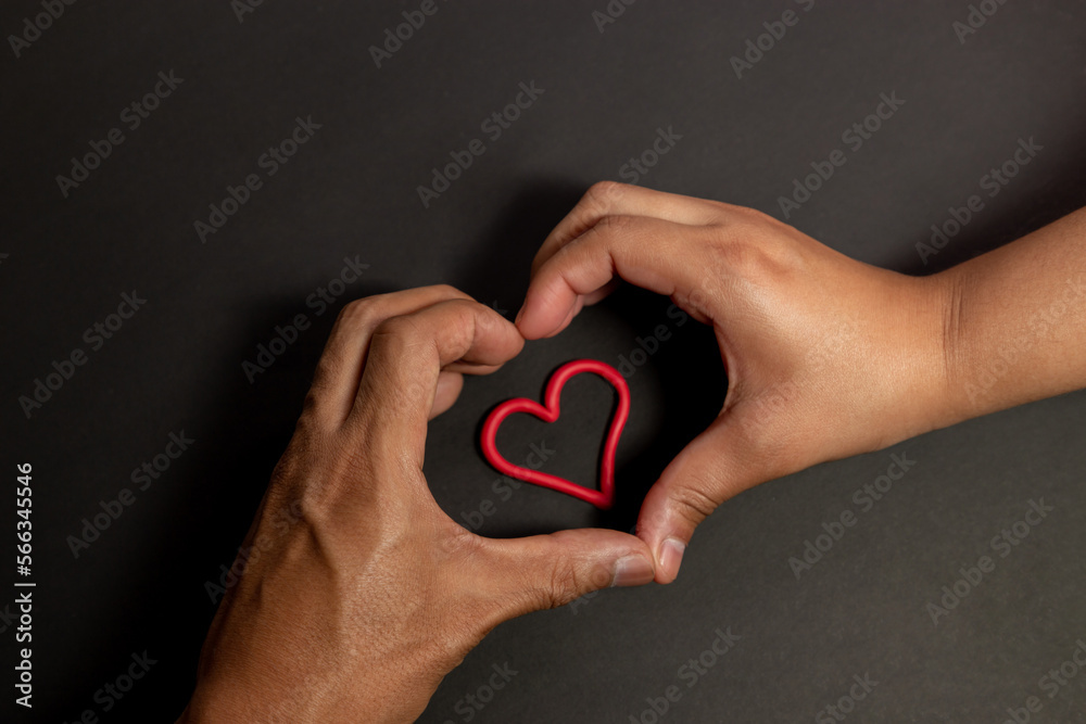 Manos formando corazón el fondo negro y corazones hechos en plastilina ...