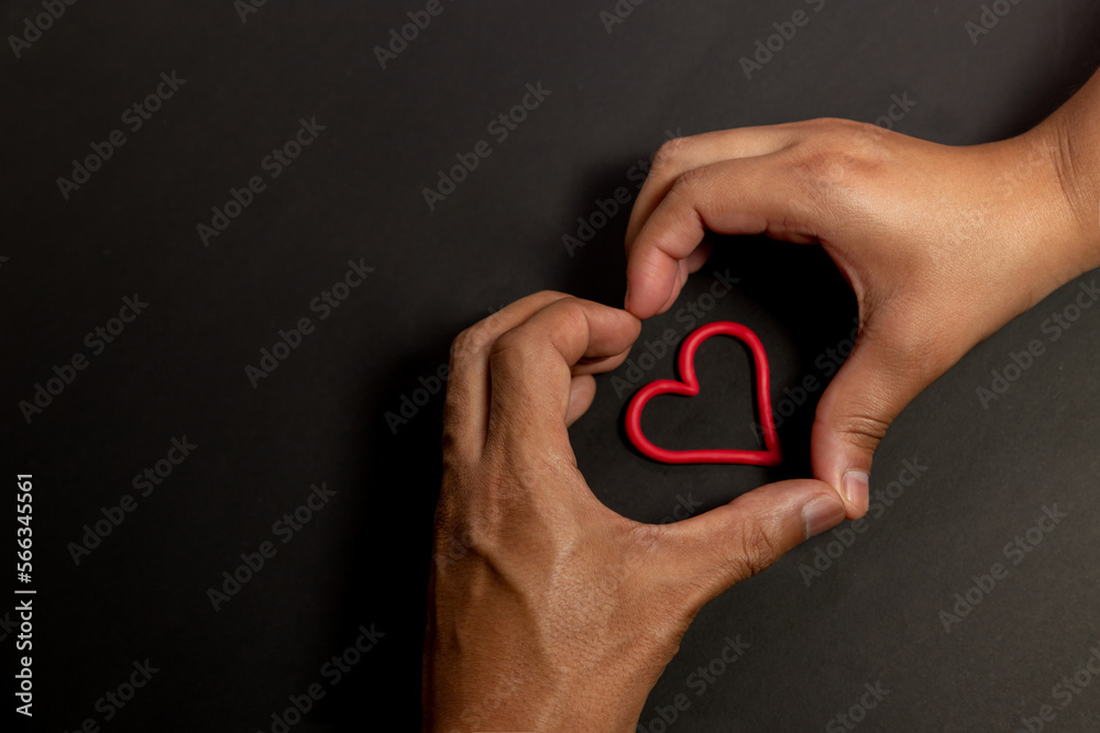 Manos formando corazón el fondo negro y corazones hechos en plastilina ...