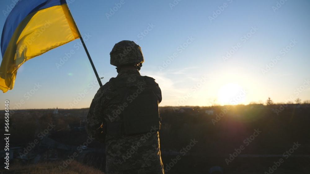 Soldier of ukrainian army stands at hill and holds waving flag of ...