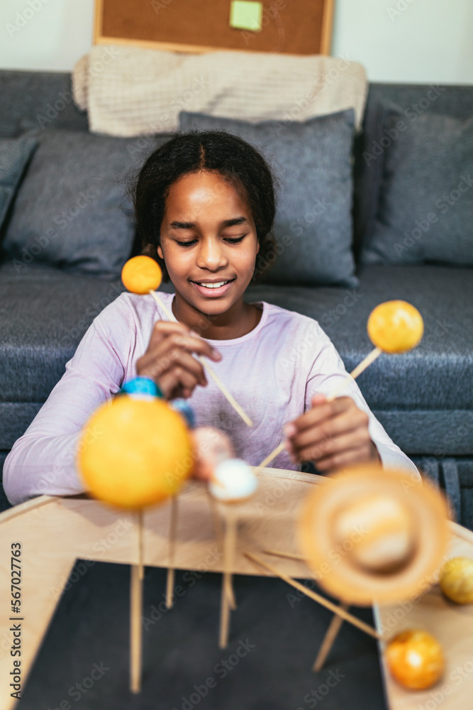 Happy african american school girl making a solar system for a school ...