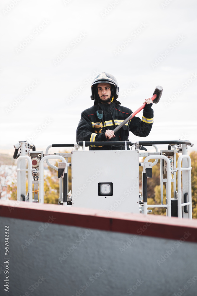 Vertical photo of a uniformed firefighter climbing on a basket of a ...