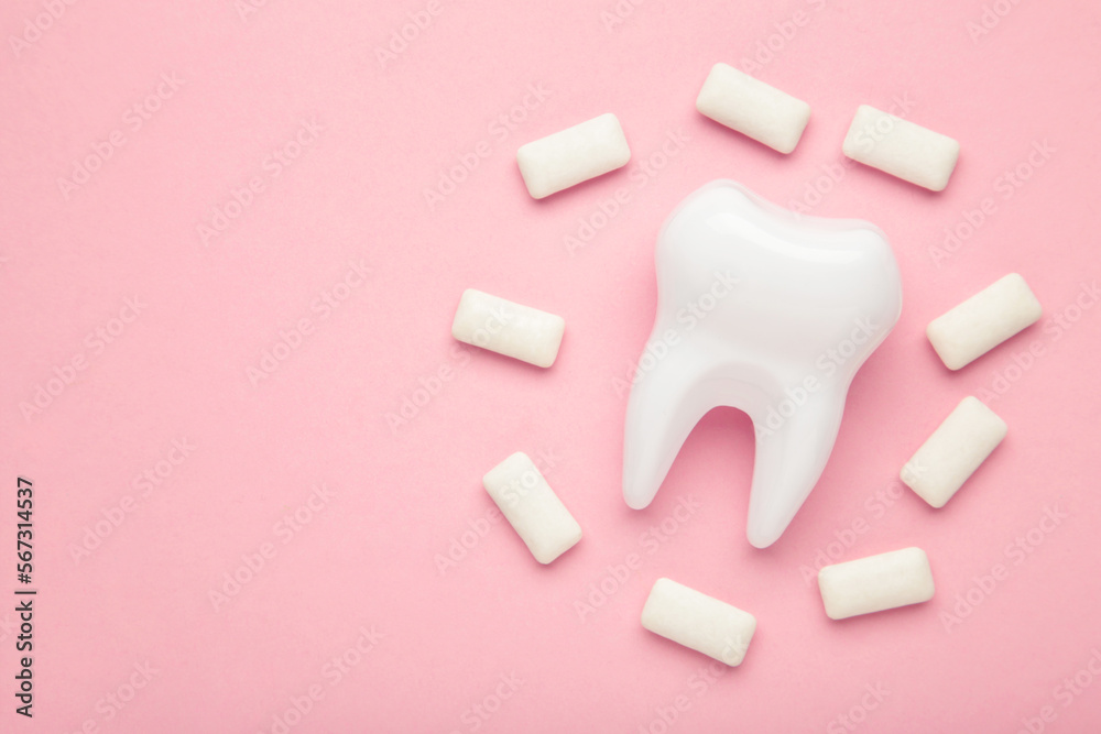 White healthy tooth model and heap of chewing gums on pink background ...