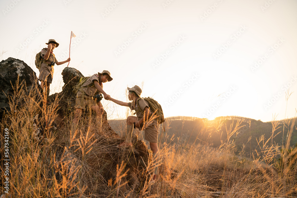 Asian boy scout teams pull their hands up a rocky cliff during a long ...
