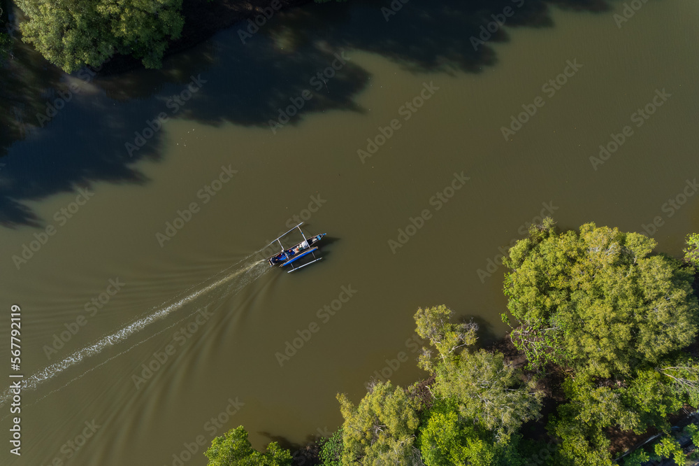 Aerial view of a boat sailing on a muddy river in a mangrove forest ...