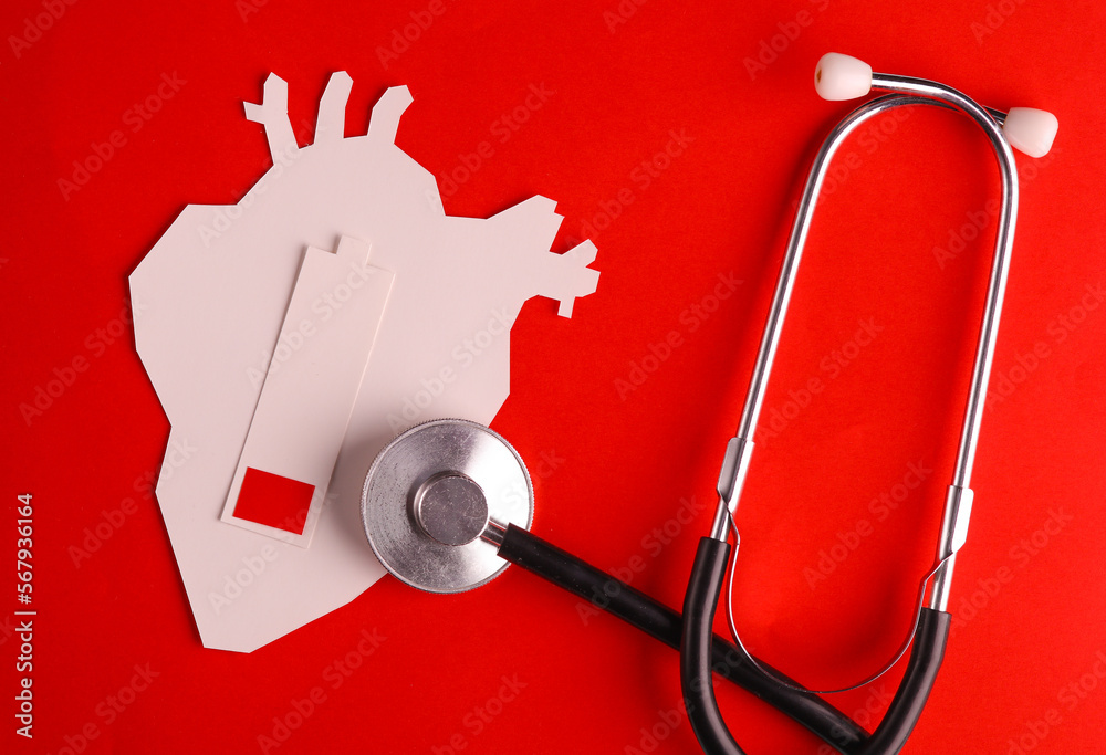 Paper cut anatomical heart and low battery, stethoscope on red ...