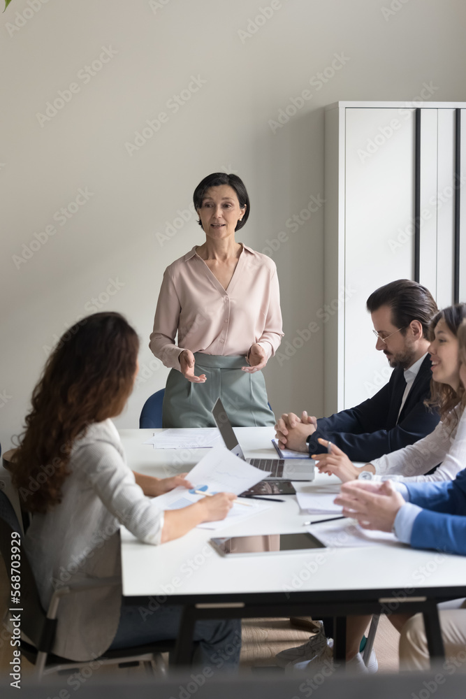 Confident senior corporate coach woman giving seminar to business team ...