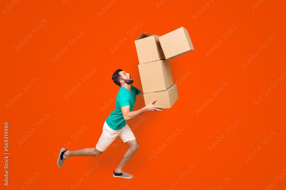 Funny nervous man is carrying his stuff in boxes to the recently bought flat. He is holding ...