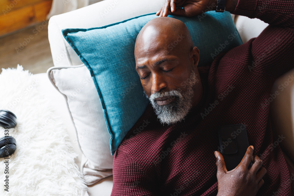 Foto de Stock High angle view of bald african american senior man with mobile phone sleeping on ...