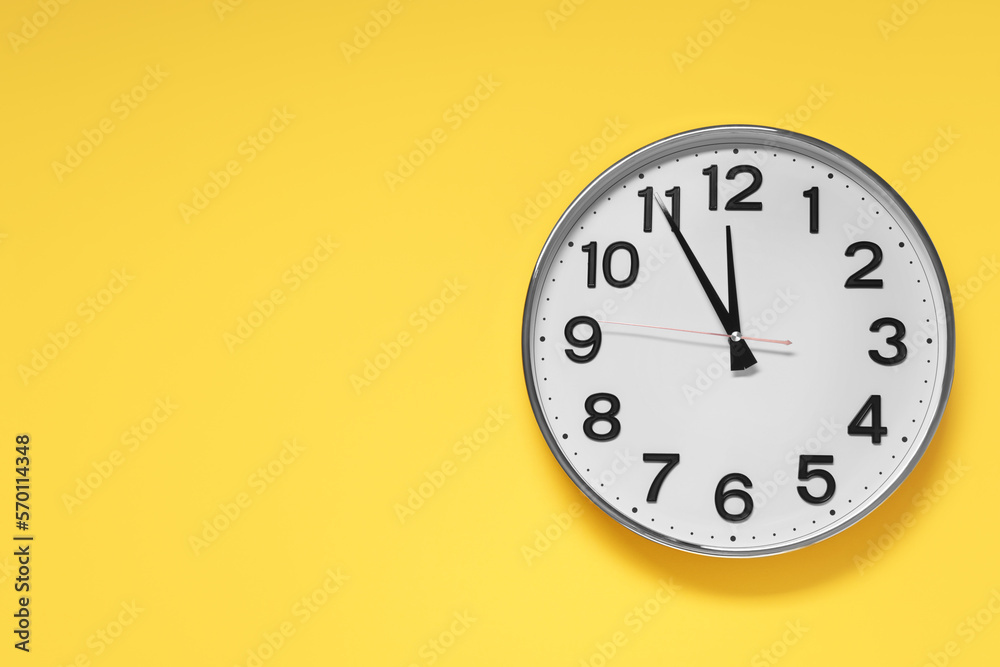 Clock showing five minutes until midnight on yellow background, top ...