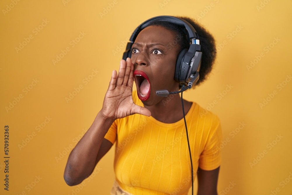 African woman with curly hair standing over yellow background wearing ...