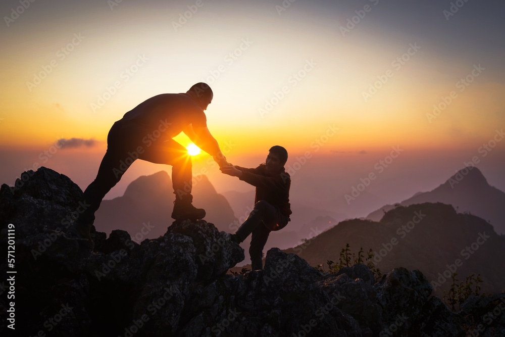 Silhouette Two Male hikers climbing up mountain cliff and one of them ...