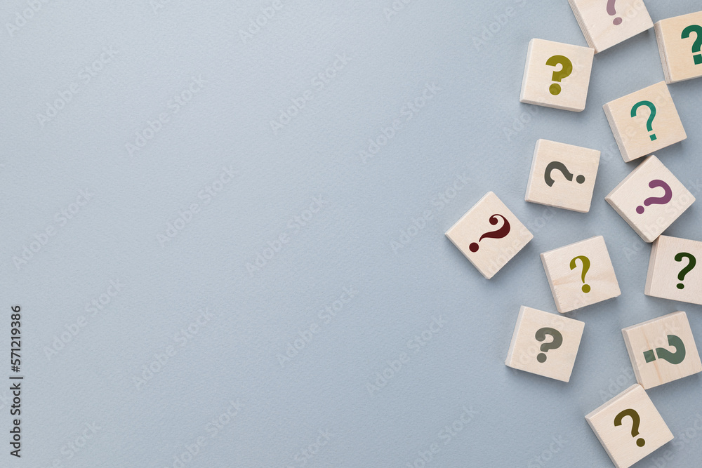 Many question mark signs on wood blocks on gray paper background with ...