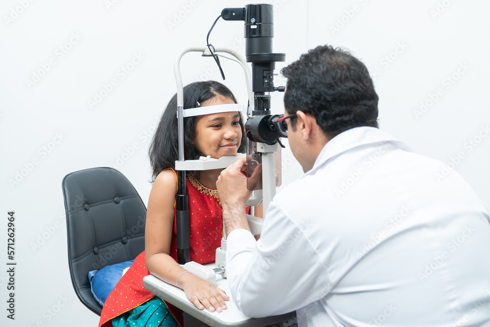 little cute Indian girl child patient is getting eyes exam from ...