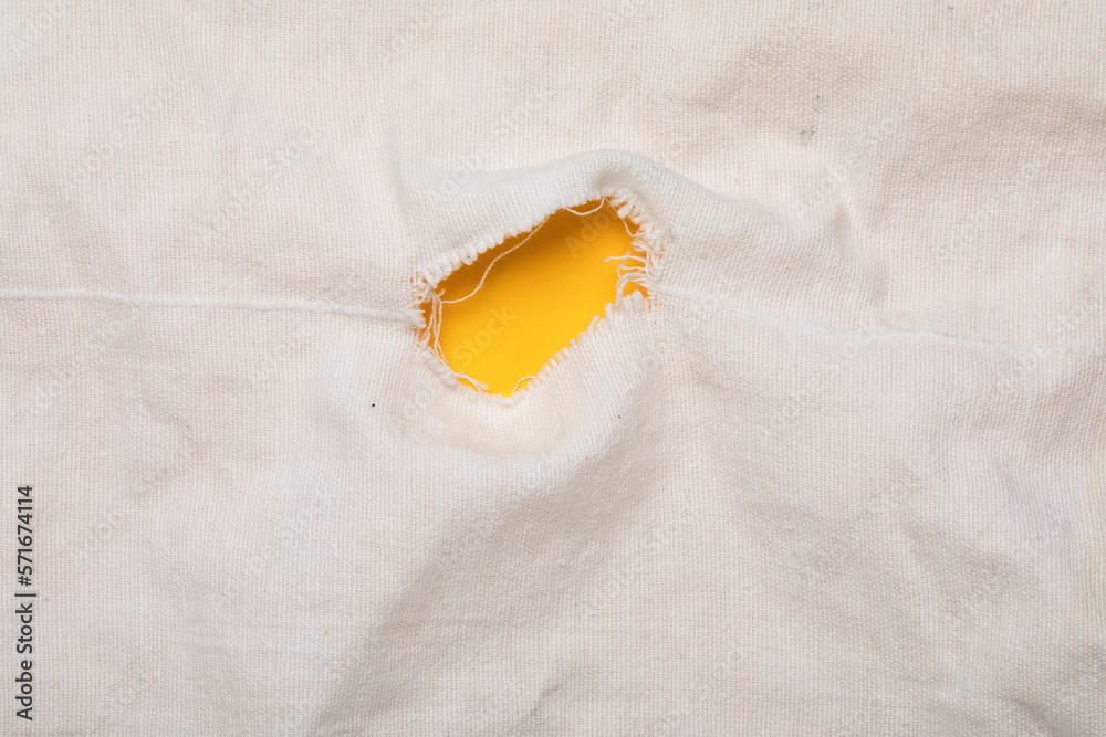 white cotton fabric with big hole and shredded threads, ripped open ...
