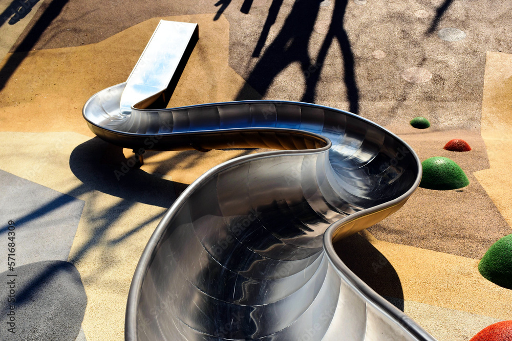 shiny stainless steel slide with playful humps in public playground ...