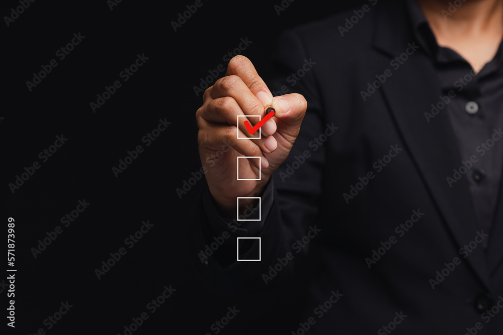 Businessman holding a pen and checking a mark on the boxes symbol is ...
