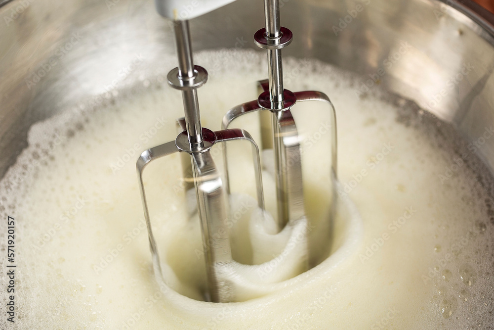 Beating egg whites with a hand mixer until stiff Stock Photo | Adobe Stock
