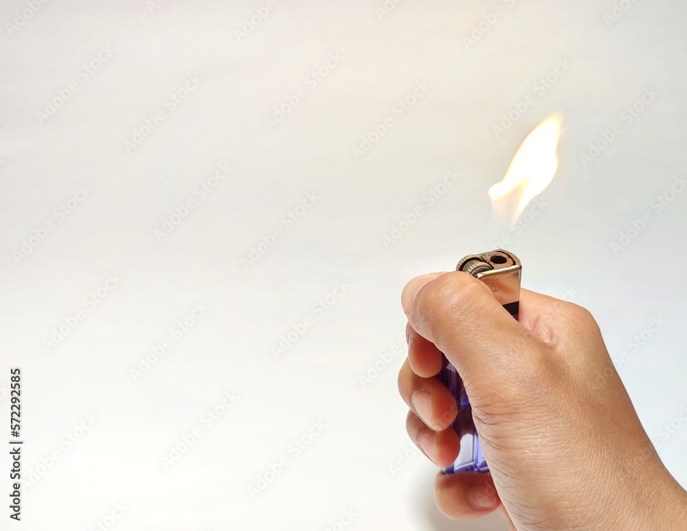 Portrait of hand turning on hand-held gas lighter or cricket lighter ...