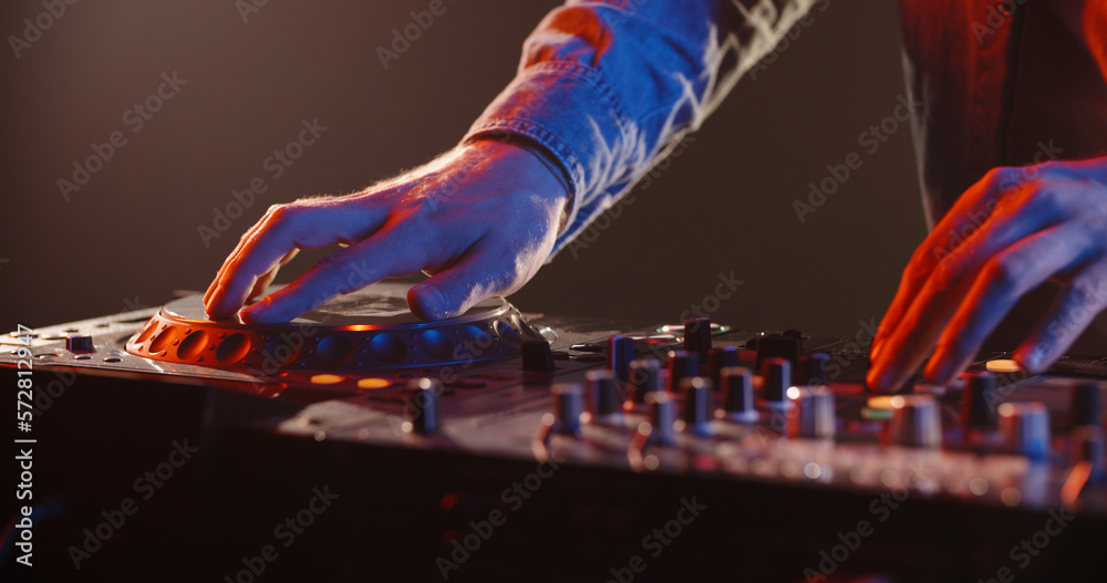 Disc jockey working on his professional mixer controller, sliding the ...
