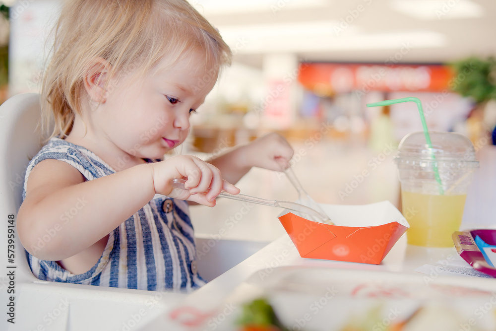 Some fast food with the family. Little girl eats in a cafe. The cute ...