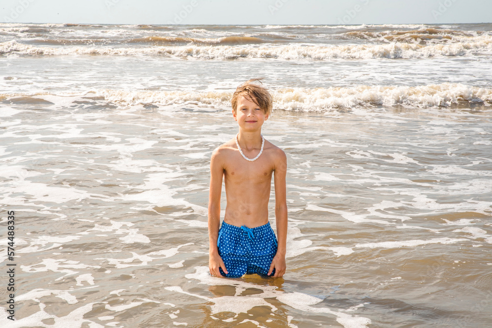 Photo Stock Young Child Preteen Boy Standing in the Surf at the Beach on a Sunny Day | Adobe Stock