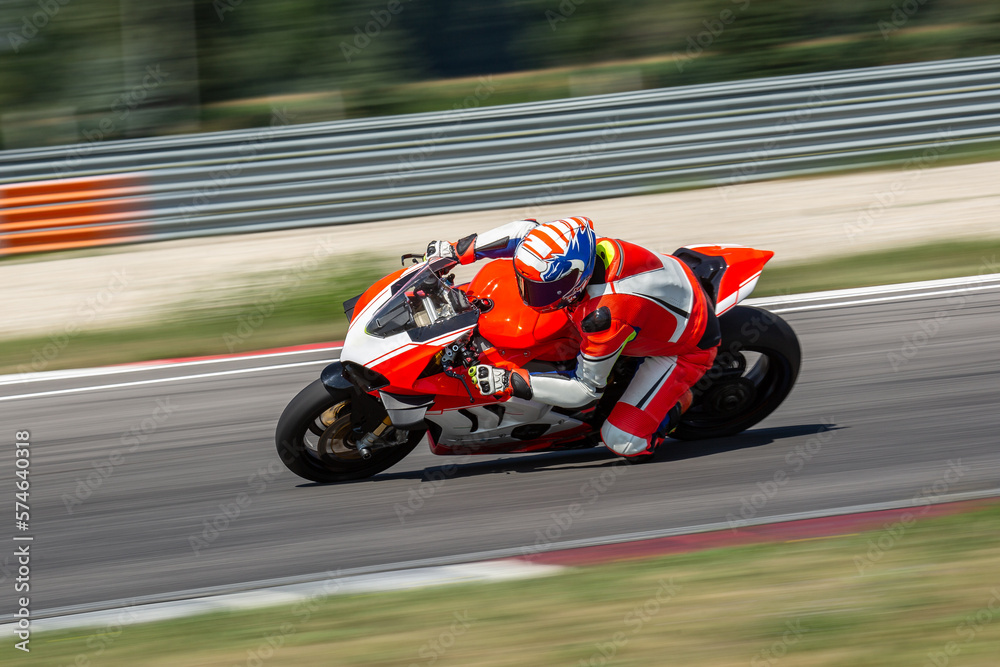 A motorcycle rider riding on an white,orange sport motorcycle through a ...