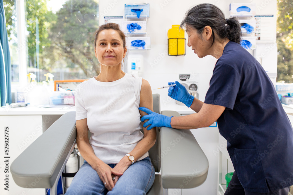 Female patient getting an injection on the arm by a female healthcare ...