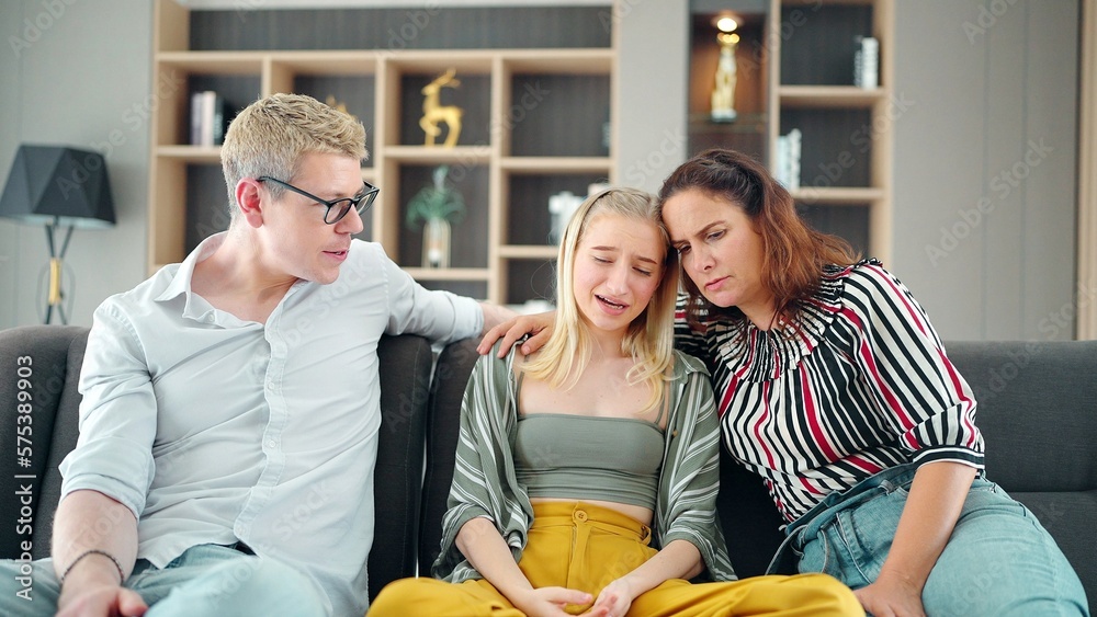 Worried mom and dad comforting depressed teen daughter bonding at home. Family loving ...