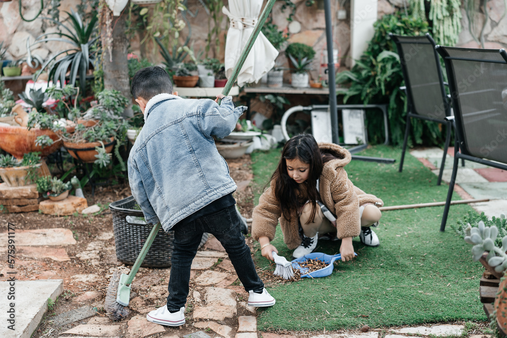 Little children cleaning backyard in springtime. Boy and girl sweeping ...