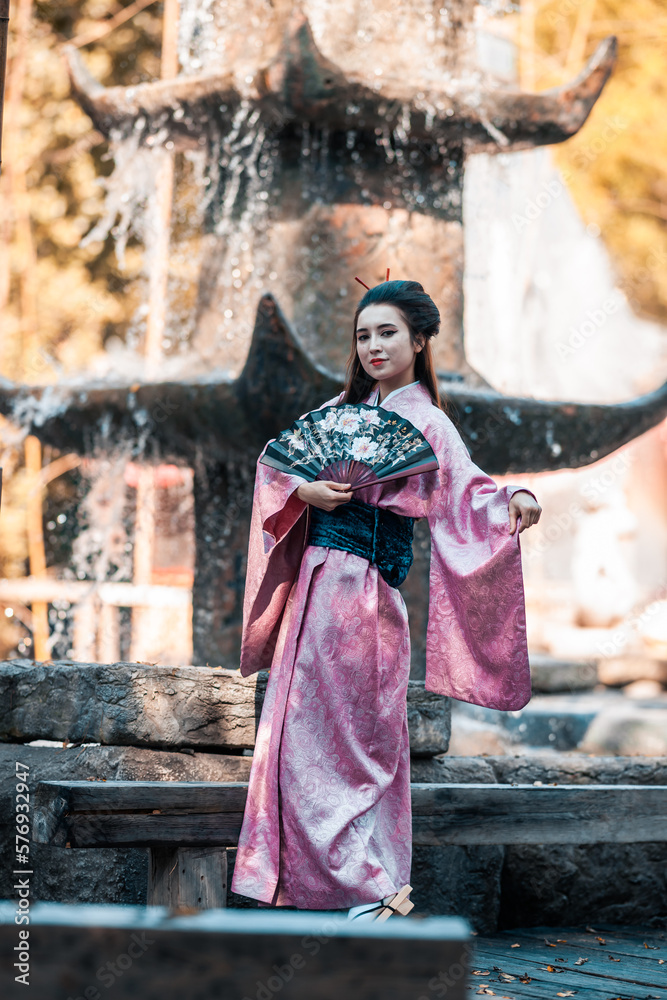Japanese geisha in a traditional kimano with a fan and armed with a ...