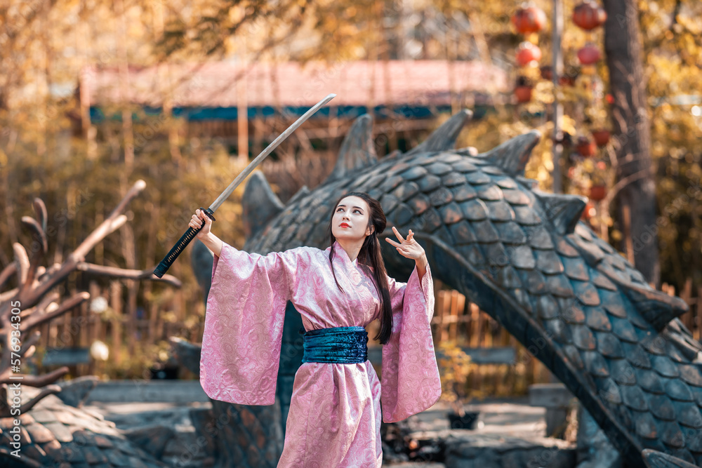 Japanese geisha in a traditional kimano with a fan and armed with a ...