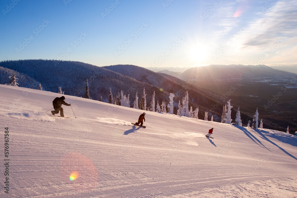Two Skiers And A Snowboarder Makes A Turn On A Snowy Landscape In ...