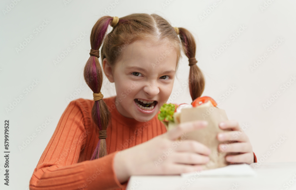 Portrait of funny little girl biting sandwich with a grin on her face ...