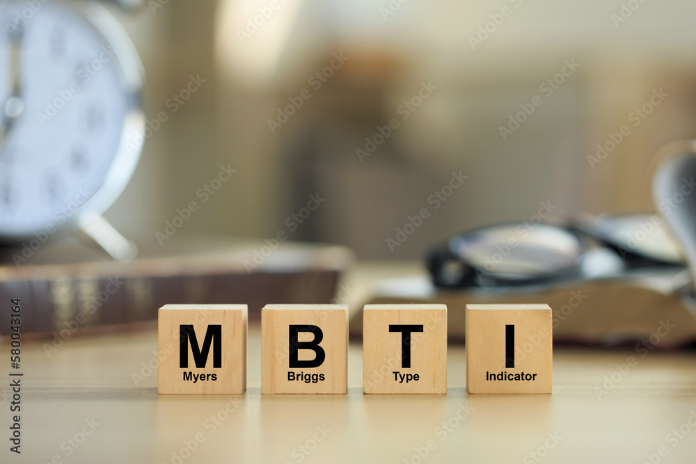 wooden blocks with the letters MBTI on the table with books ...