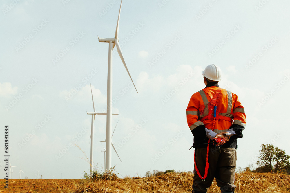 Back view male engineer technician standing looking at wind turbine ...