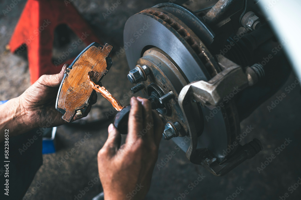 Auto mechanic applying a copper anti-seize on back of car brake pads ...