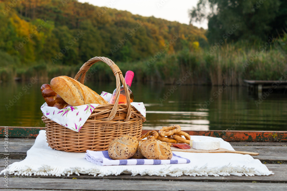 Picnic basket near a beautiful lake with wine and blanket. Relaxing ...