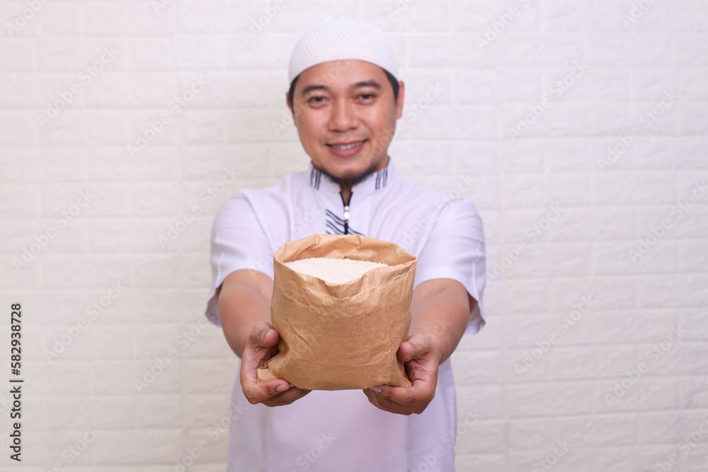 Asian Muslim man hand giving alms bag of rice isolated on white ...