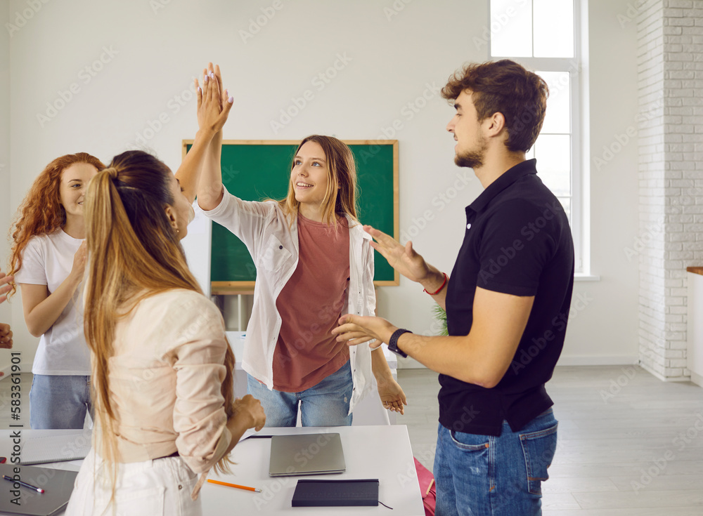 Students in class, two teen girls are giving five each other another ...