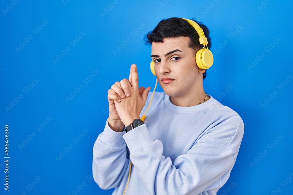 Non binary person listening to music using headphones holding symbolic ...